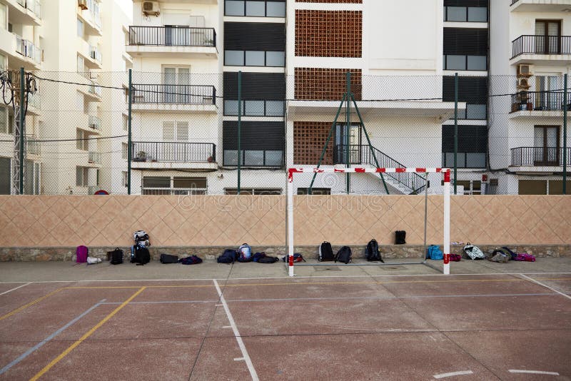 School Yard with Backpacks and Buildings in the Background Stock Image ...