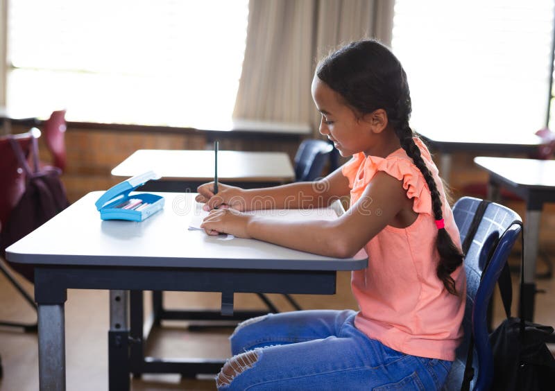 In School, Young Girl Writing in Notebook at Desk, Concentrating on ...