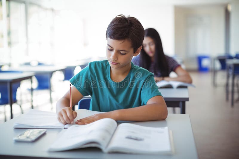 Schoolboy Doing Homework in Classroom Stock Photo - Image of classroom ...