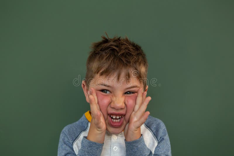 Schoolboy with Hands on Face and Surprised Against Greenboard in a ...