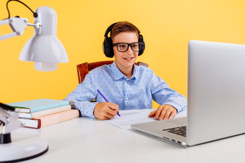 Schoolboy in Headphones, Doing Homework Using a Laptop Computer ...