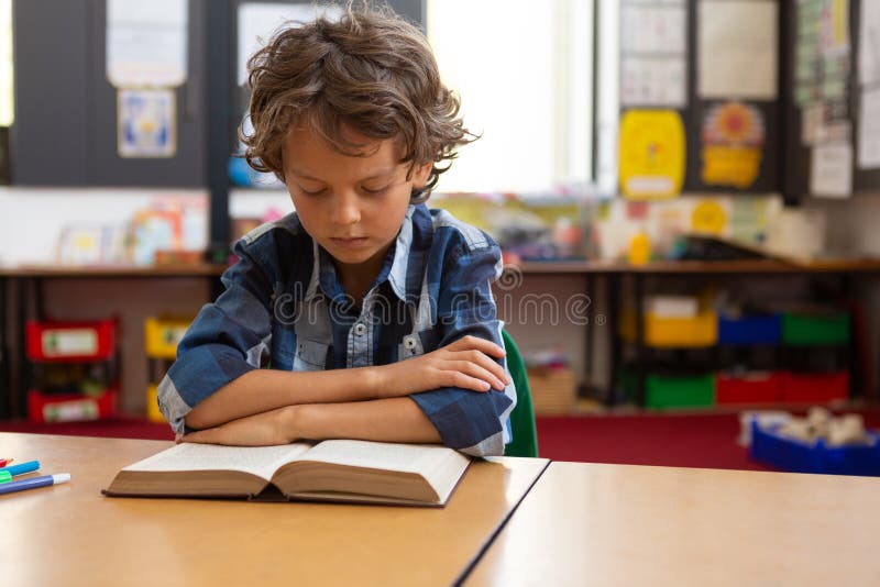 Schoolboy Reading a Book in the Classroom Stock Photo - Image of ...