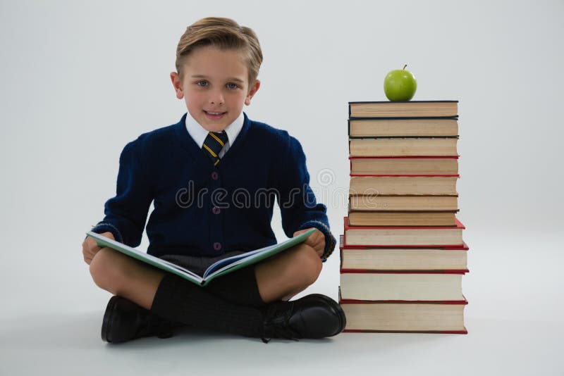 Schoolboy Reading Book while Sitting beside Books Stack Stock Photo ...