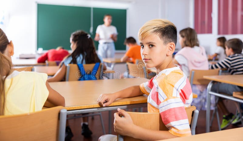 Schoolboy Sits Half-turned at Desk in Classroom at Lesson in Elementary ... Schoolboy Sits Half-turned at Desk in Classroom at Lesson in Elementary ...