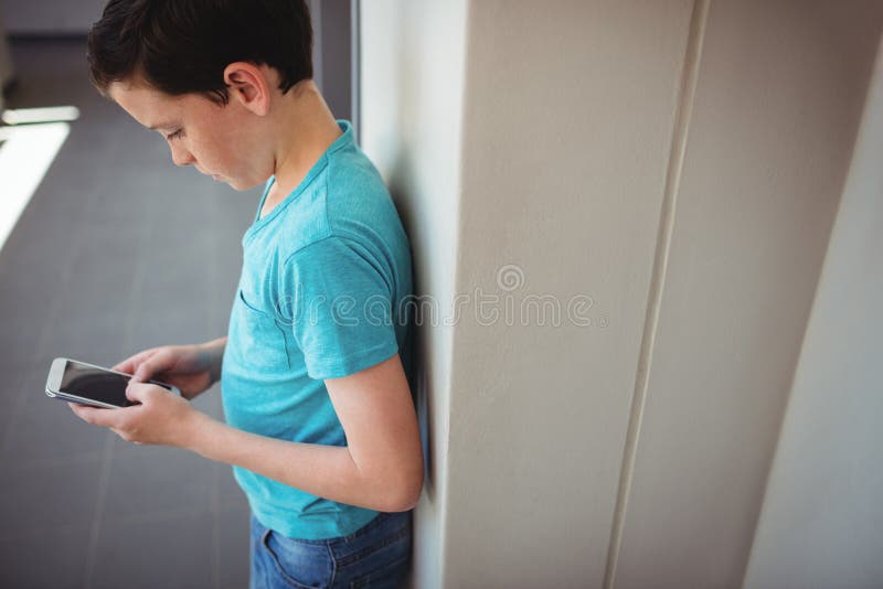 Schoolboy Using Mobile Phone in Corridor at School Stock Image - Image ...