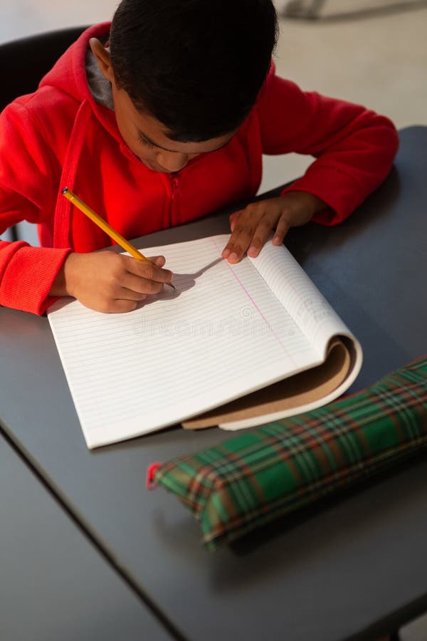 Schoolboy Writing in a Notebook at Desk in Classroom Stock Photo ...