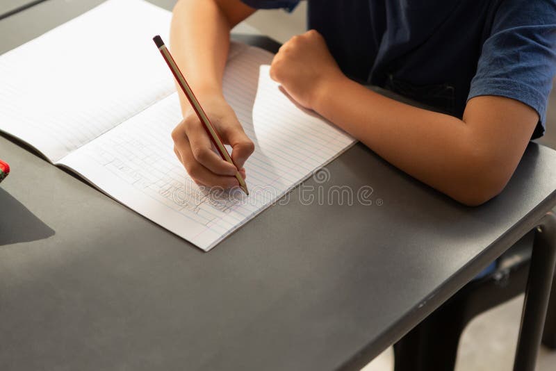 Schoolboy Writing in a Notebook at Desk in Classroom Stock Image ...