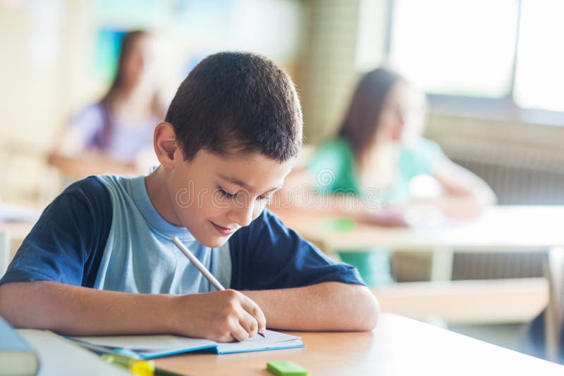 Children Sitting at Desk and Writing in Classroom Stock Image - Image ...