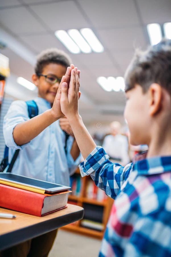 Schoolboys Giving High Five while Schoolgirls Studying in Classroom ...