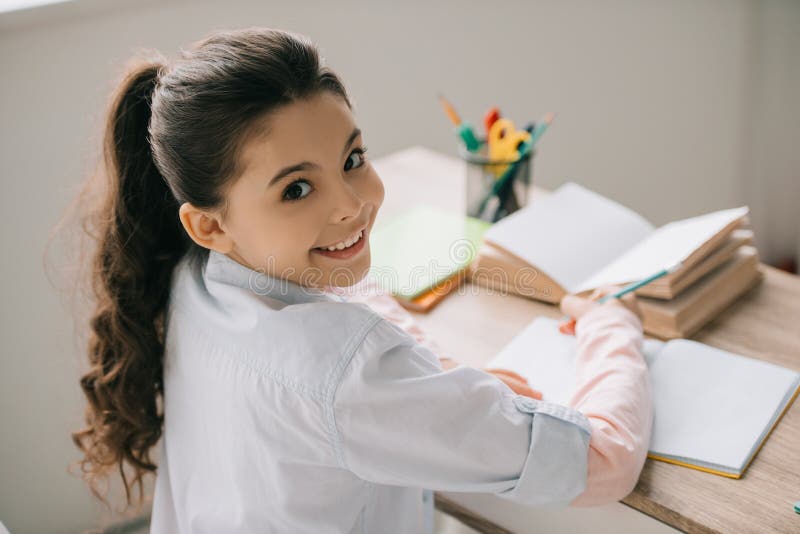 Schoolchild Looking at Camera while Sitting at Desk and Doing Homework ...