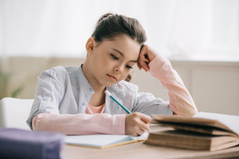 Schoolchild Writing in Notebook while Sitting at Desk and Doing ...