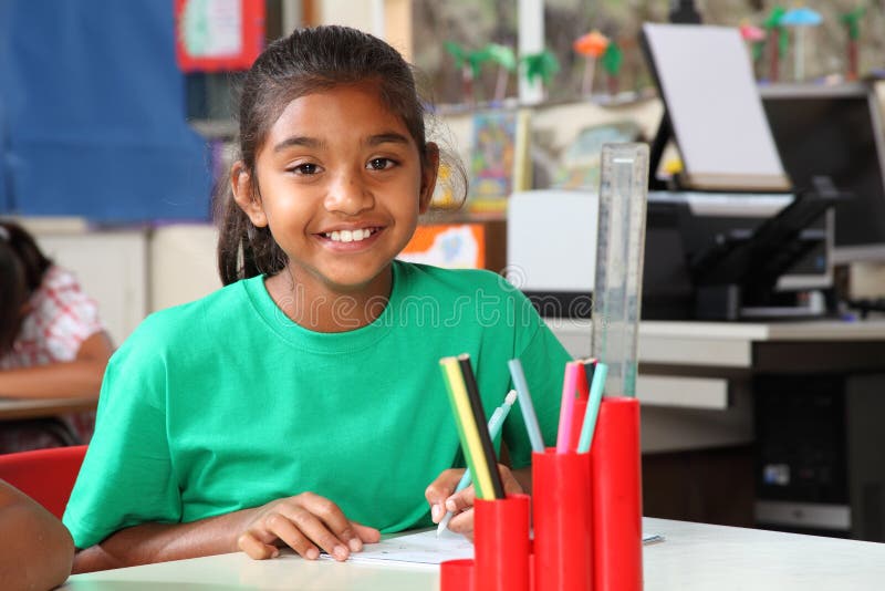 Young Schoolgirl in Classroom Busy Writing at Desk Stock Photo - Image ...