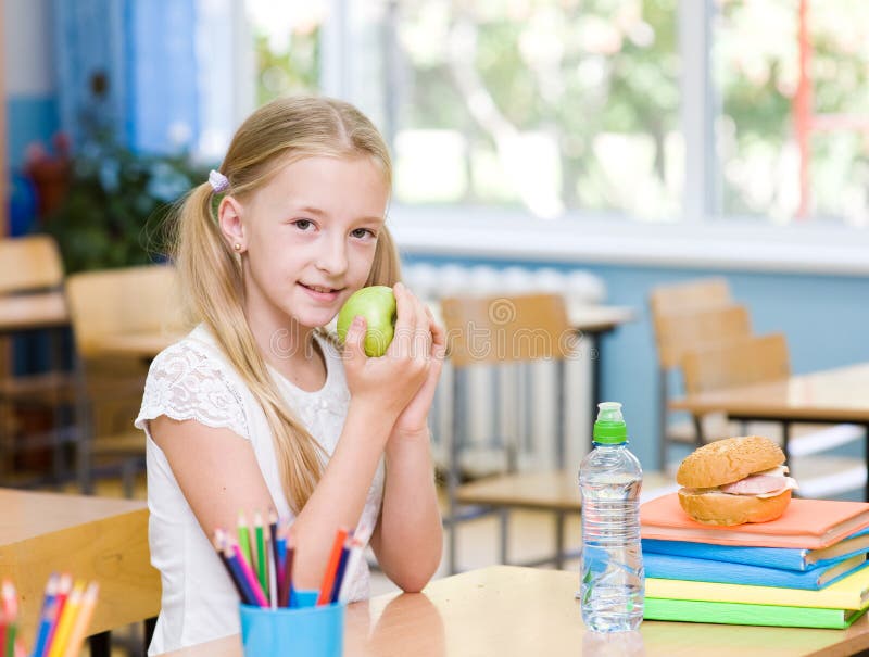Schoolgirl in the Classroom Eating a Green Apple Stock Photo - Image of ...