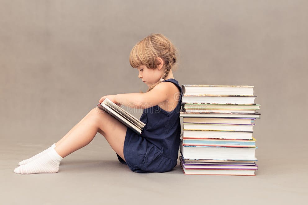 Schoolgirl Leaning on a Stack of Books and Reading Stock Photo - Image ...