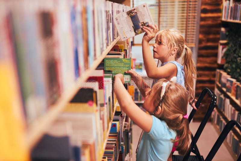 Schoolgirls Looking for Books in School Library. Students Choosing Set ...