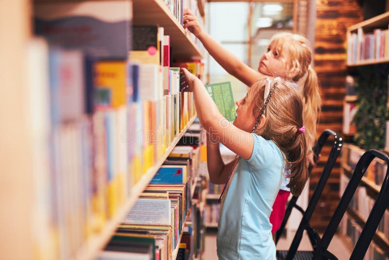 Schoolgirls Looking for Books in School Library. Students Choosing Set ...