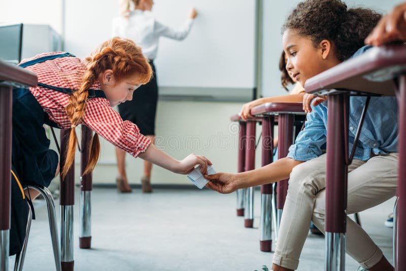Schoolgirls Passing Message in Class Stock Photo - Image of black ...