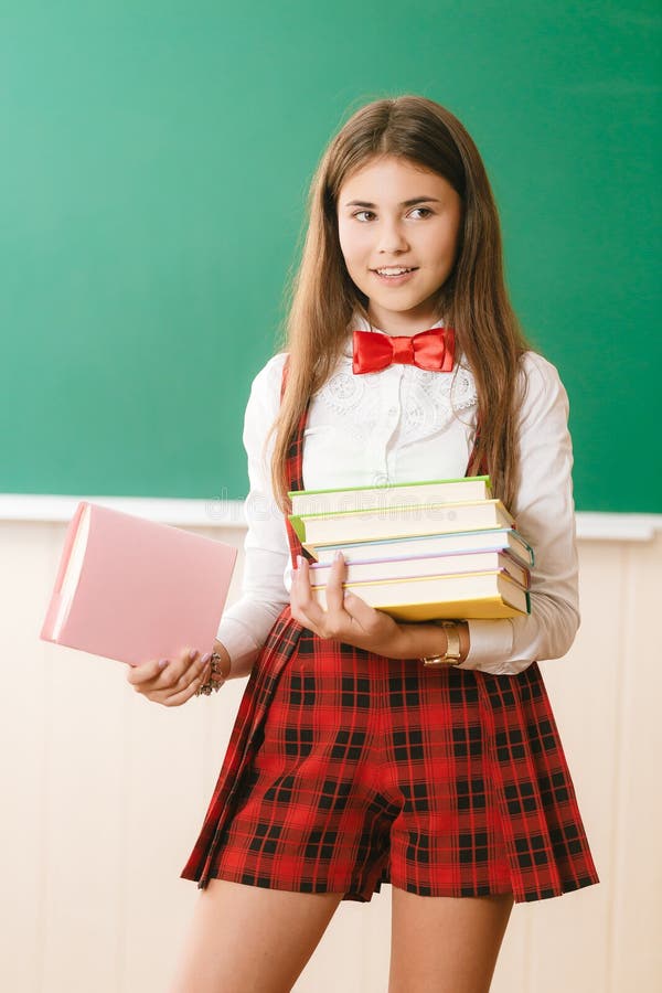 Schönes Schulmädchen In Der Roten Schuluniformstellung Mit Büchern Vor