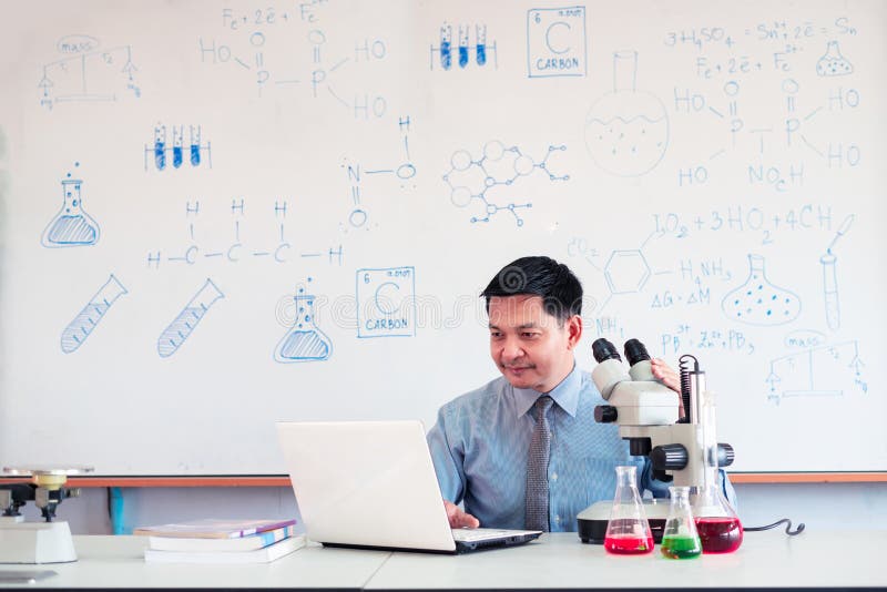 Science Chemistry Teacher Teaching Online with Microscope and Laptop in ...