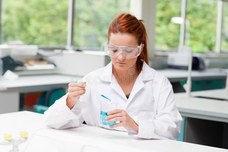 Female Scientist Wearing Lab Coat and Safety Goggles Holding Blue ...