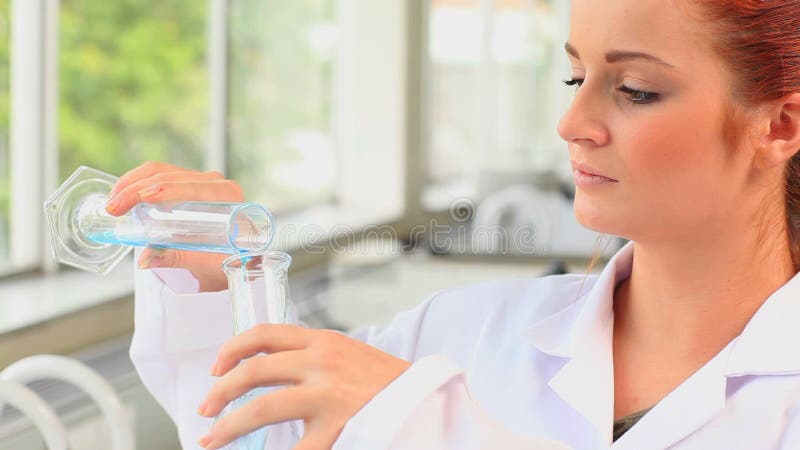Student Pouring Liquid while Her Classmate is Taking Notes Stock Video ...