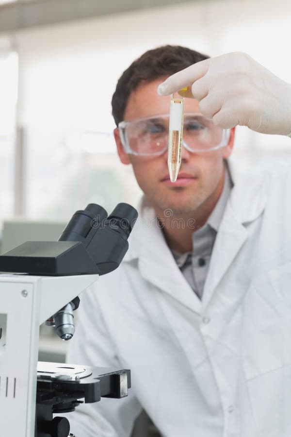 Scientific Researcher Looking at Test Tube while Using Microscope in ...