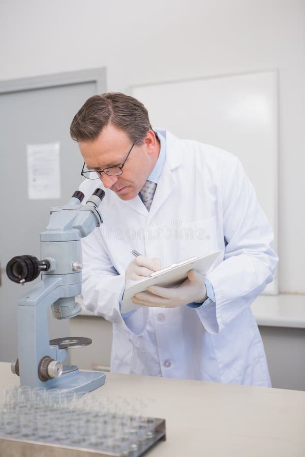 Scientist Analysing Microscope Writing on Clipboard Stock Photo - Image ...