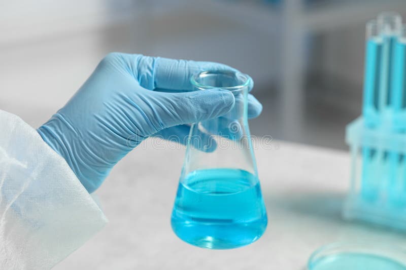 Scientist with Beaker of Light Blue Liquid in Laboratory, Closeup Stock ...