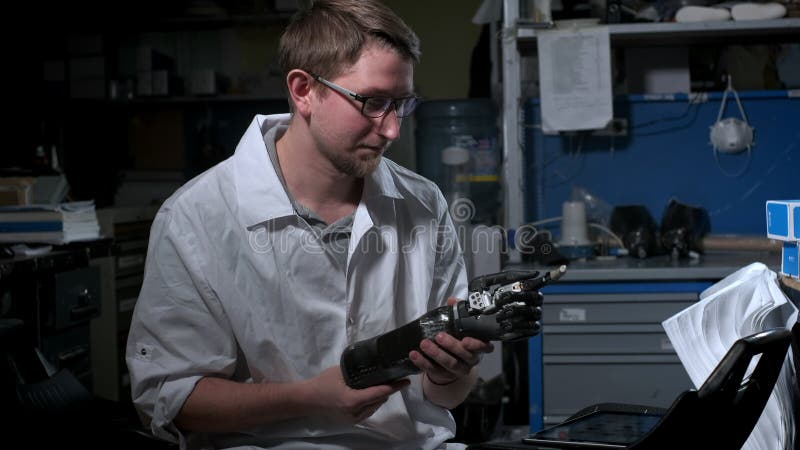 Engineer with Prosthetic Hands Works at a Factory, Drilling a Wooden ...