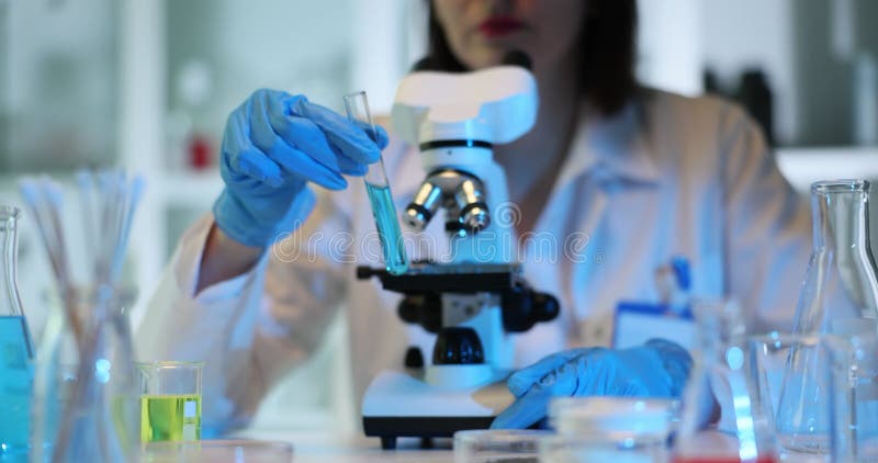 Scientist Examining a Blue Liquid Sample Under a Microscope Stock ...