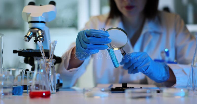 Scientist Examining Blue Liquid Sample Using Magnifying Glass Stock ...