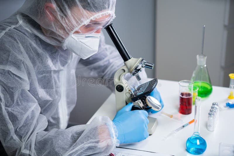Scientist Examining Sample with a Microscope, Doing Medical Research in ...