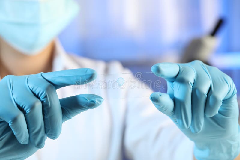Scientist Holding Microscope Slide with Light Blue Sample in Laboratory ...