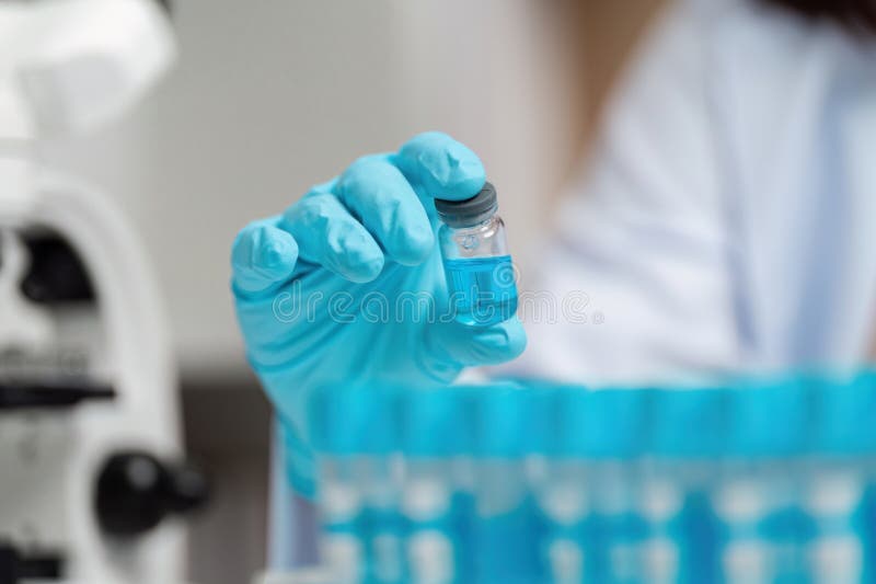 Scientist Holding a Vial of Blue Liquid in a Modern Laboratory Setting ...