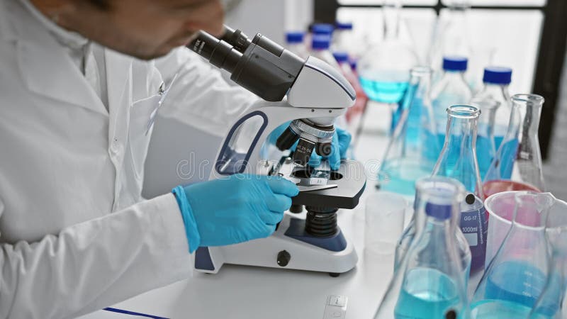 Scientist in Lab Coat Inspecting Specimen Under Microscope in Modern ...