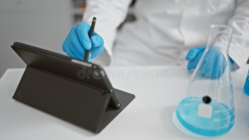Scientist in Lab Coat Using Tablet To Record Data with Blue Chemical Solution in Flask on Bench ...