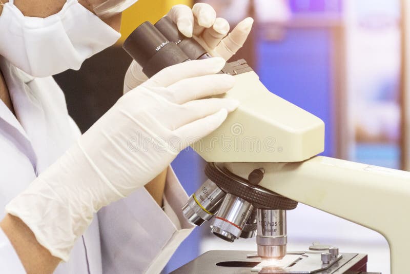 Scientist Looking through a Microscope Doing Research in a Laboratory ...