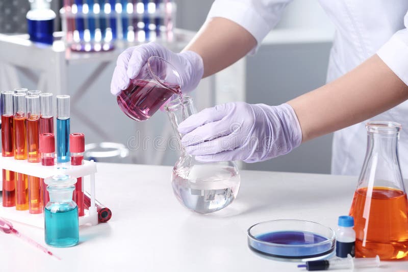 Scientist Pouring Reagent into Beaker at Table in Chemistry Laboratory ...