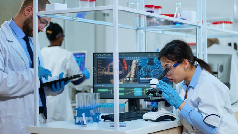 Scientist Team Analysing Results Using Microscope Stock Image - Image ...