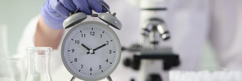 Scientist with Test Tubes, Flask and Microscope Holds Alarm Clock in ...