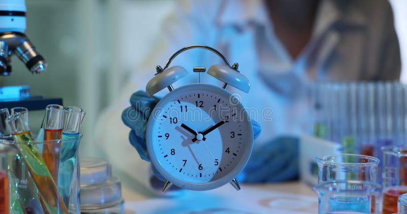 Scientist with Test Tubes, Flasks and Microscope Holds an Alarm Clock ...