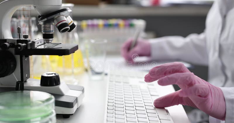 Scientist Types on Keyboard and Takes Notes on Documents in Laboratory ...