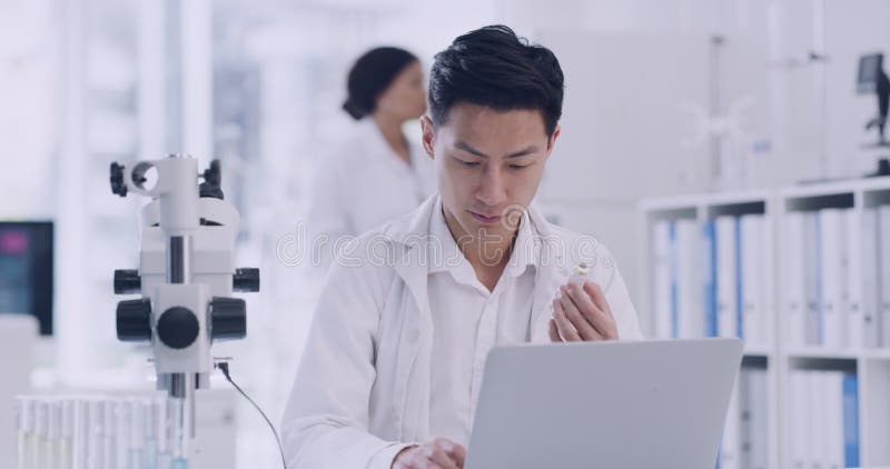 Scientist Using a Laptop while Analyzing Test Tubes of Samples in a Lab ...