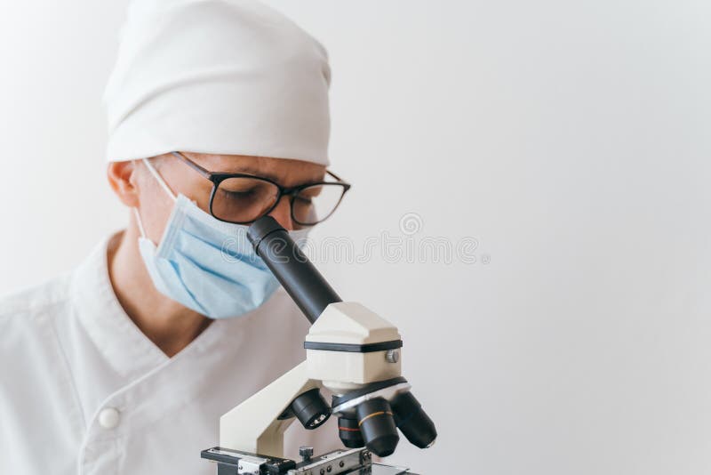 Scientist Wearing Mask Working at the Laboratory with the Microscope ...