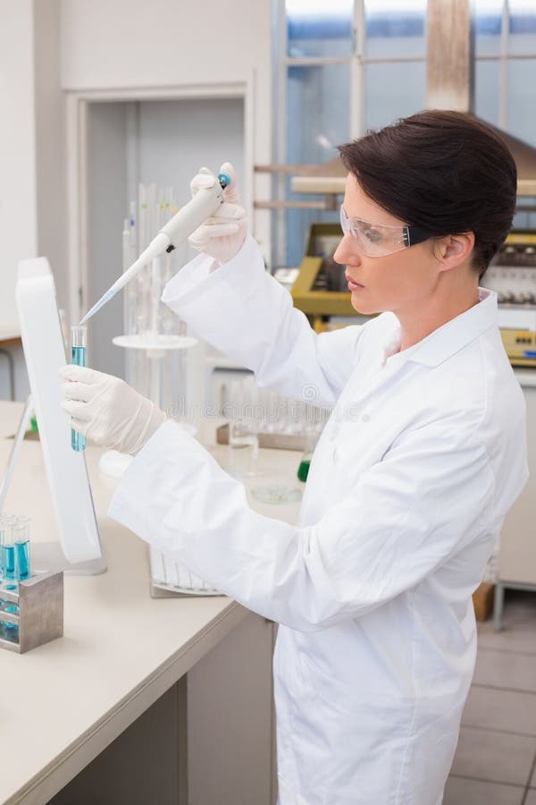 Scientist Pouring Chemical Fluid in Funnel and Her Colleague Working ...
