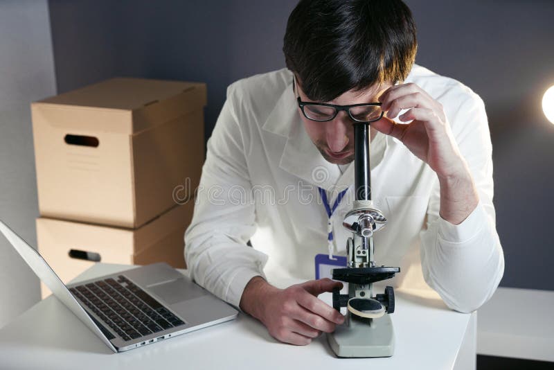 Scientist at Workspace in Laboratory with Microscope, Computer, and ...