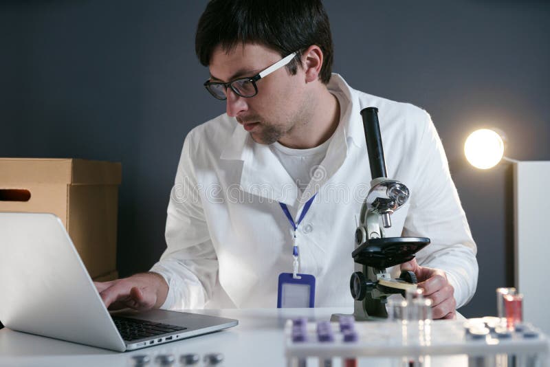 Scientist at Workspace in Laboratory with Microscope, Computer, and ...