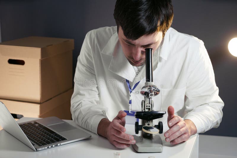 Scientist at Workspace in Laboratory with Microscope, Computer, and ...