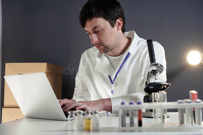 Scientist at Workspace in Laboratory with Microscope, Computer, and ...