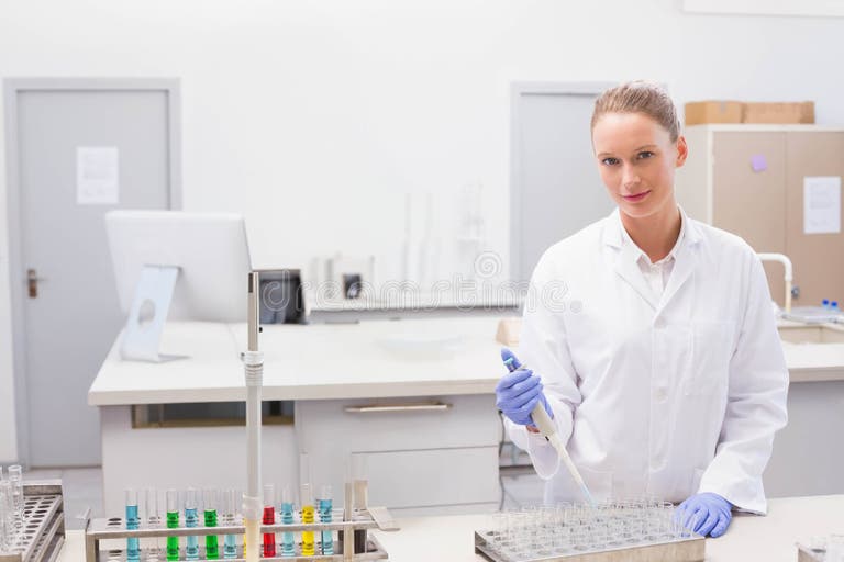 Female Scientist Wearing Lab Coat Pipetting into Multiwell Plate at Lab ...